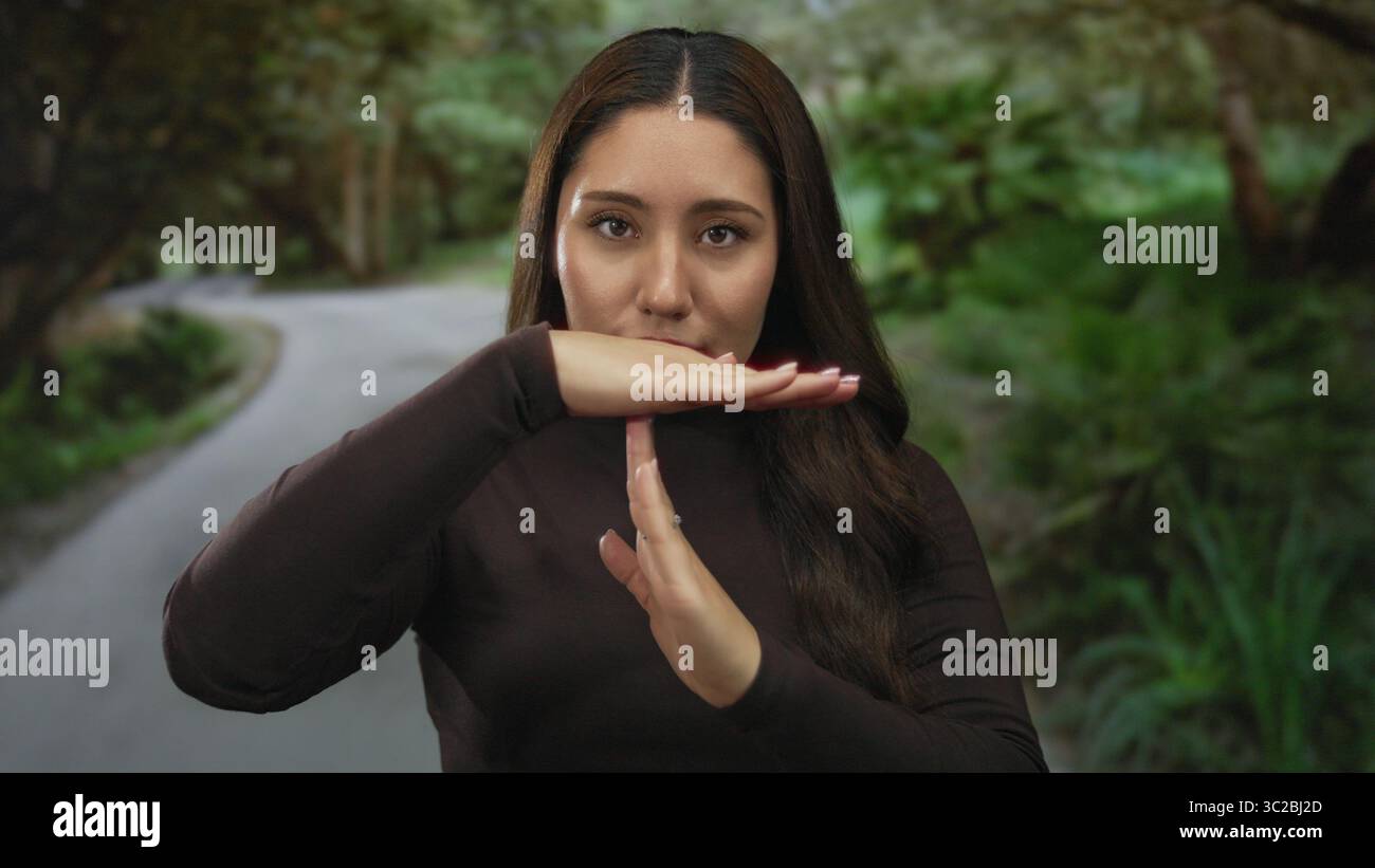 Woman standing makes timeout gesture with hands on green forest curving ...