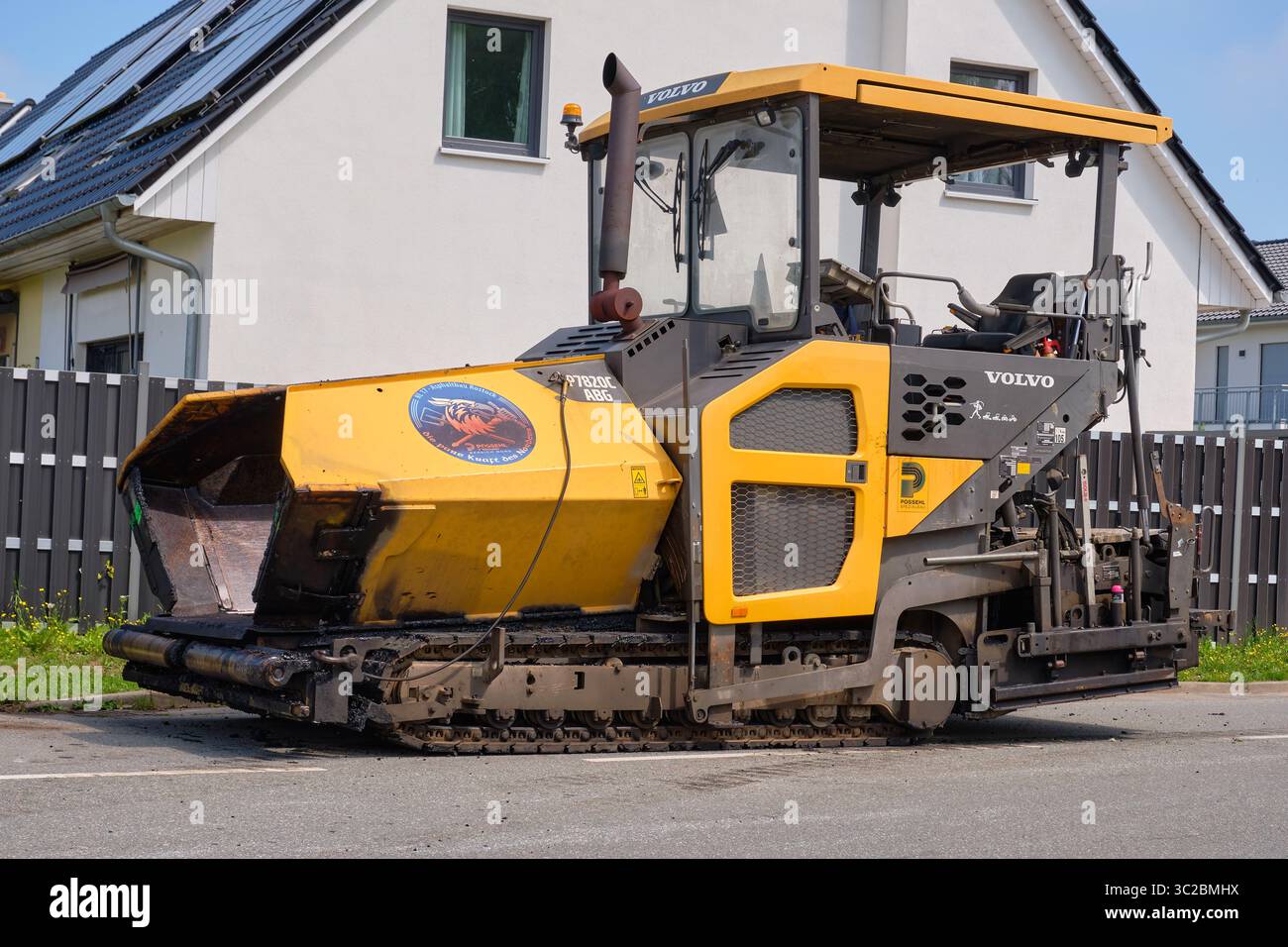 July 18, 2025 – Rostock-Germany: Yellow Volvo tracked asphalt paver ...