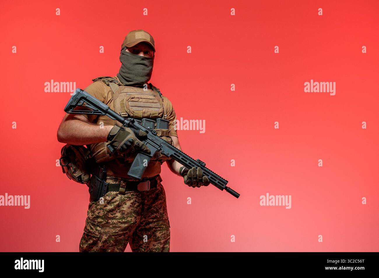A soldier in military uniform holds a rifle AR 15 in his hands on red ...