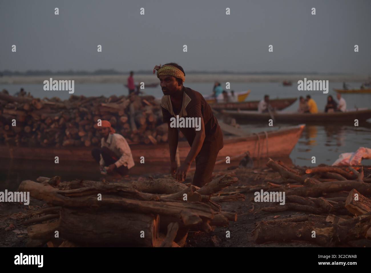 April 9, 2019: Varanasi, India: A man carries logs from a boat and ...