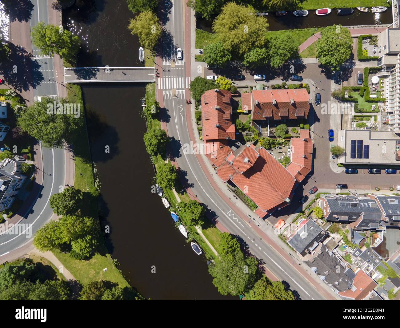 Aerial view of a canal curving through lush greenery, lined with boats ...