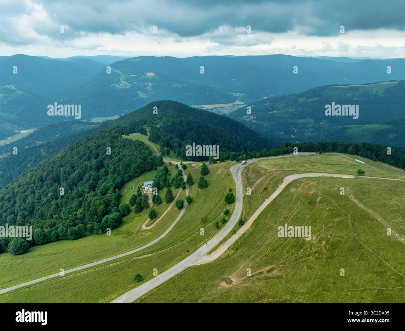 Aerial view of a winding road snakes through verdant hills, connecting ...