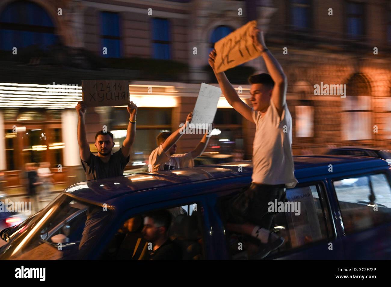 Men with placards stand in the windows of a car during a protest action ...