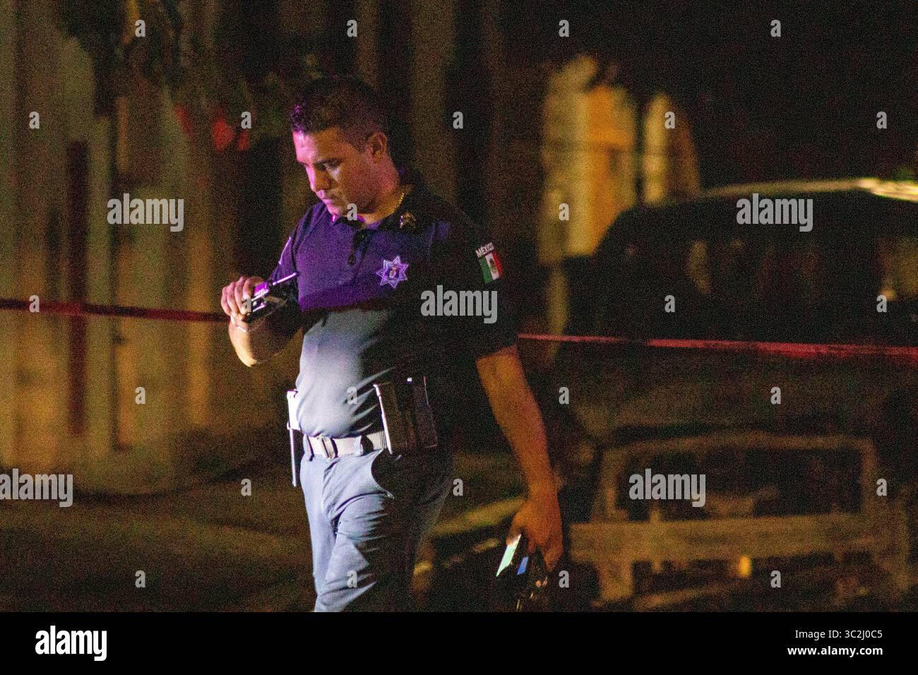 A police officer investigates a crime scene at night in Ciudad Juarez ...