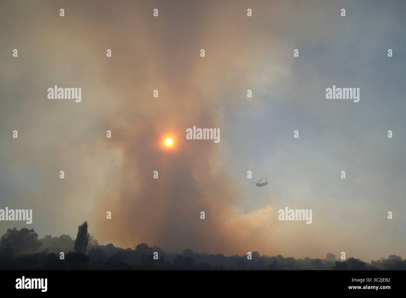 A helicopter drops water over a fire at Omodos village, Cyprus, during ...