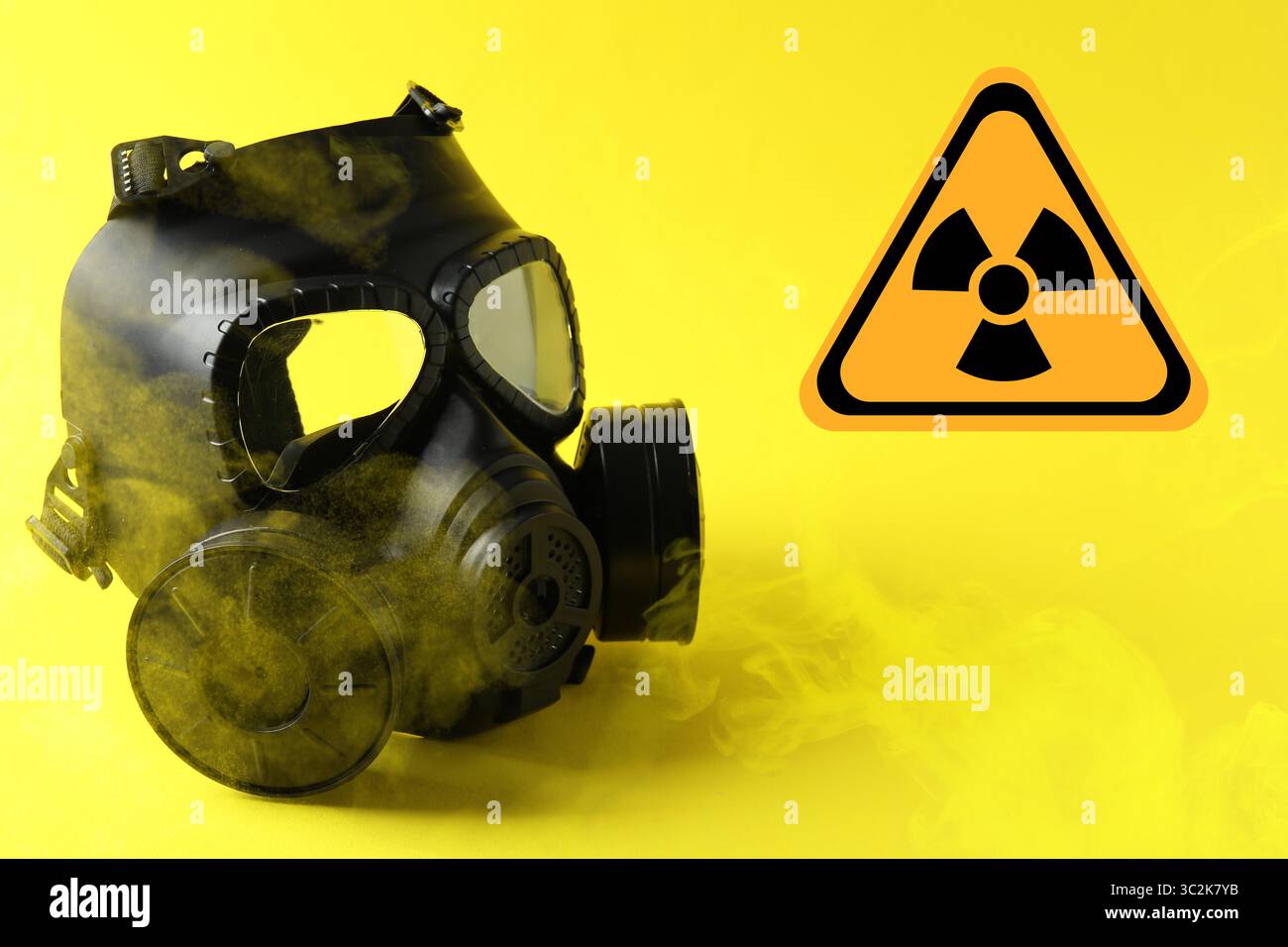 Radiation threat. Gas mask, radioactive sign and smoke on yellow ...