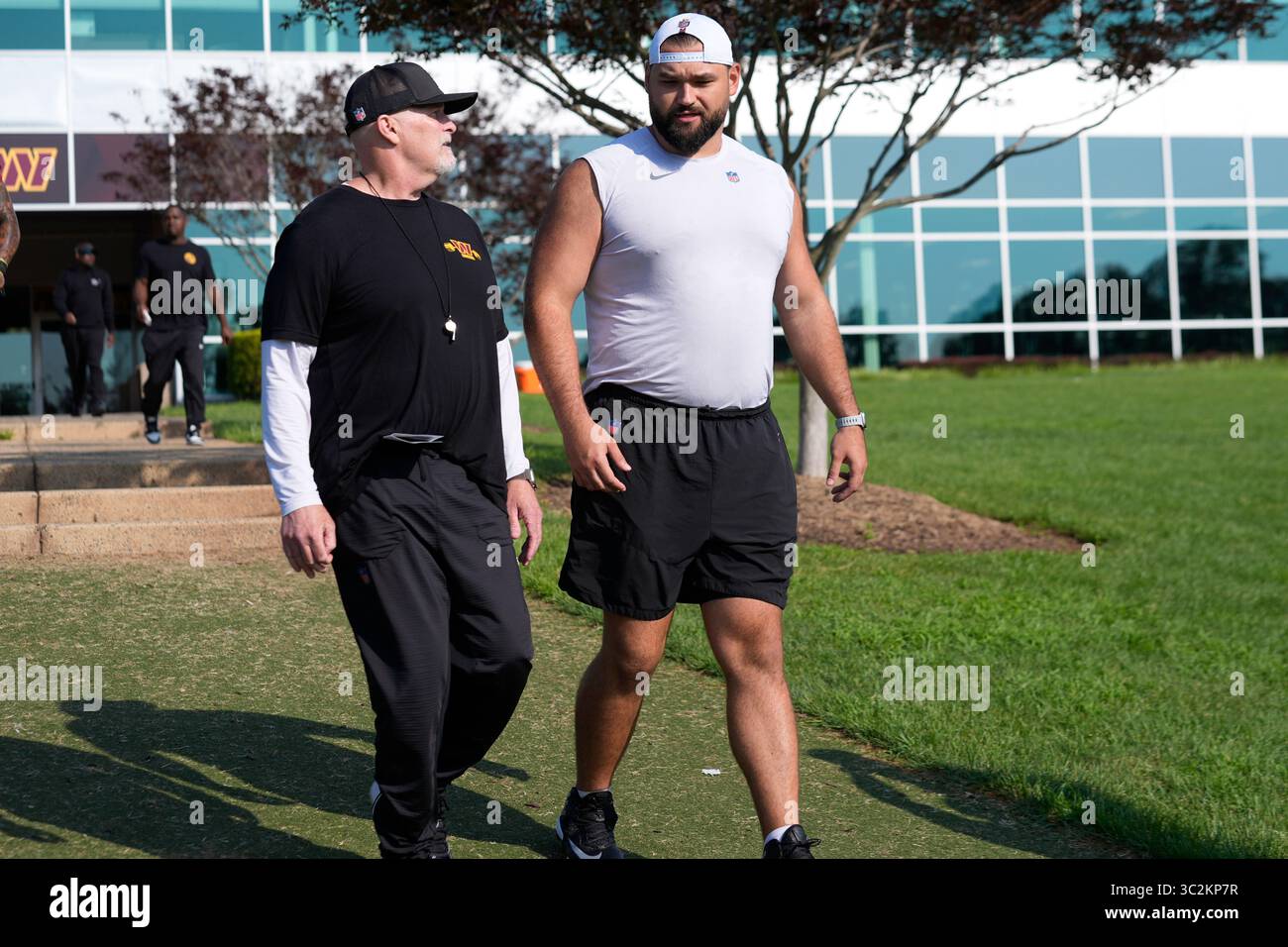 Washington Commanders head coach Dan Quinn walks with guard Sam Cosmi ...