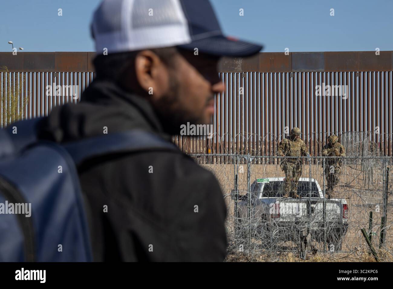 Civilian man watches as officers patrol behind barbed wire at Ciudad ...