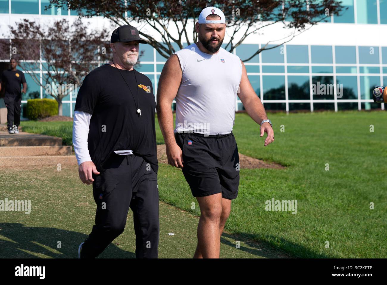 Washington Commanders head coach Dan Quinn walks with guard Sam Cosmi ...