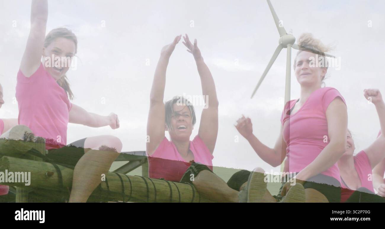 Cheering six women wearing pink tops sitting on log obstacle at wind ...
