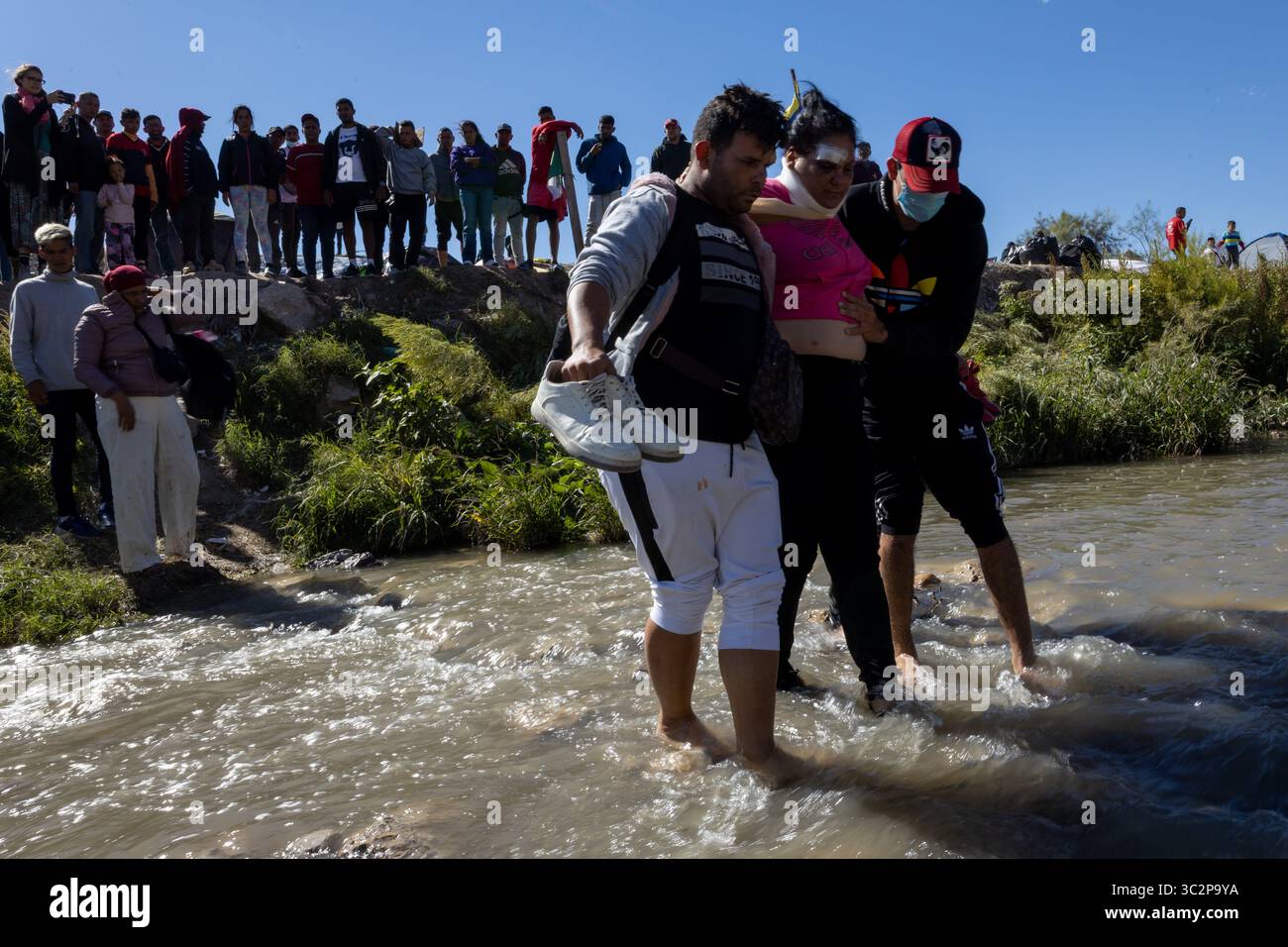 Migrants cross a river at the Ciudad Juarez border, helping each other ...