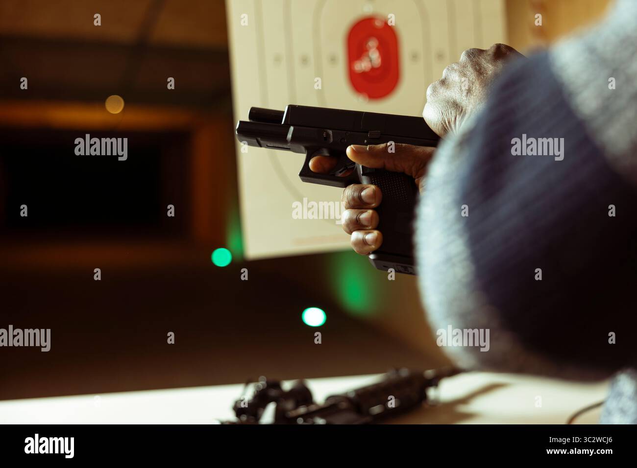 Indoor shooting range client cocking handgun, setting mechanism up for ...