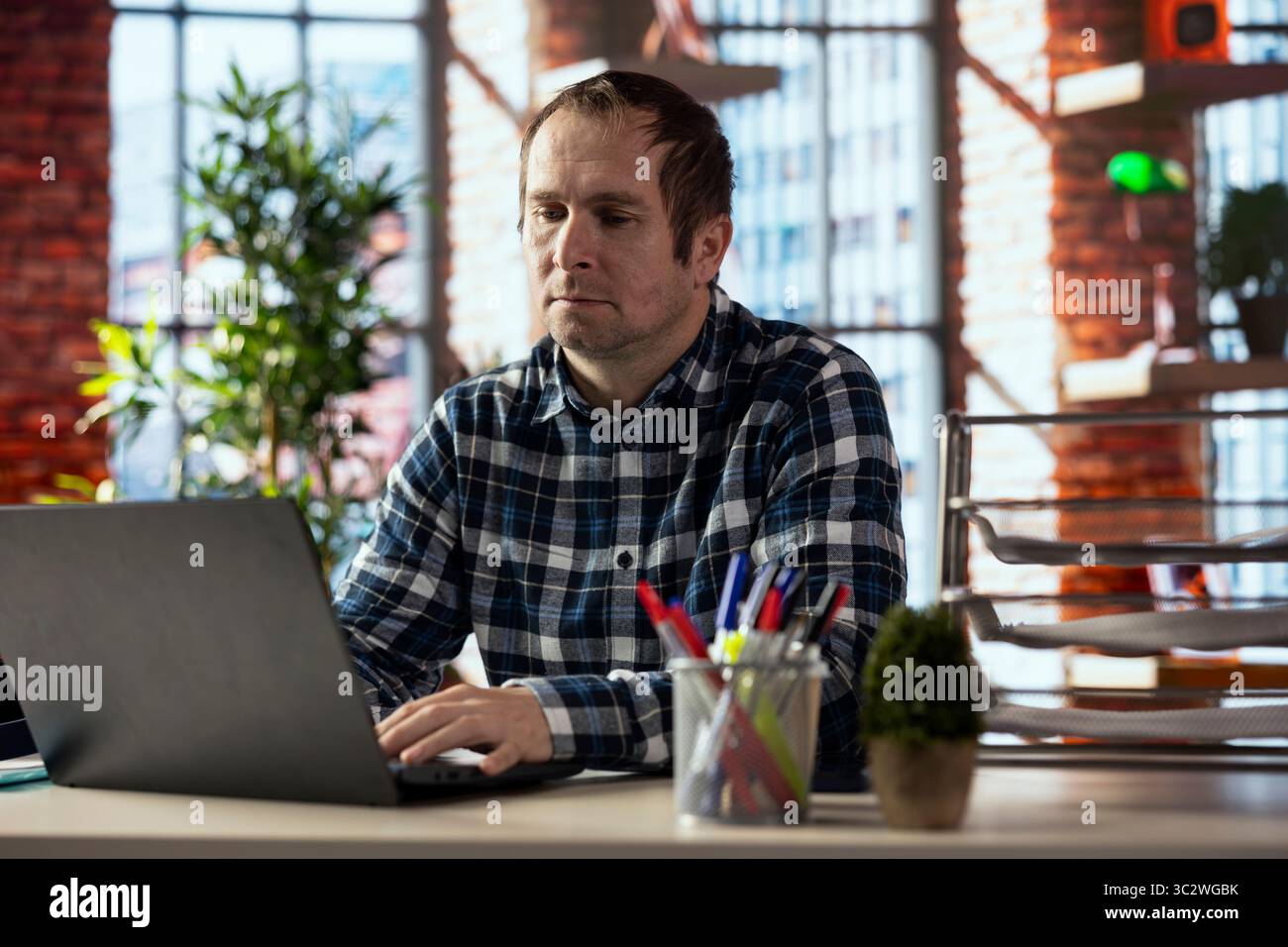 Employee at desk completing spreadsheets on laptop, entering numerical ...