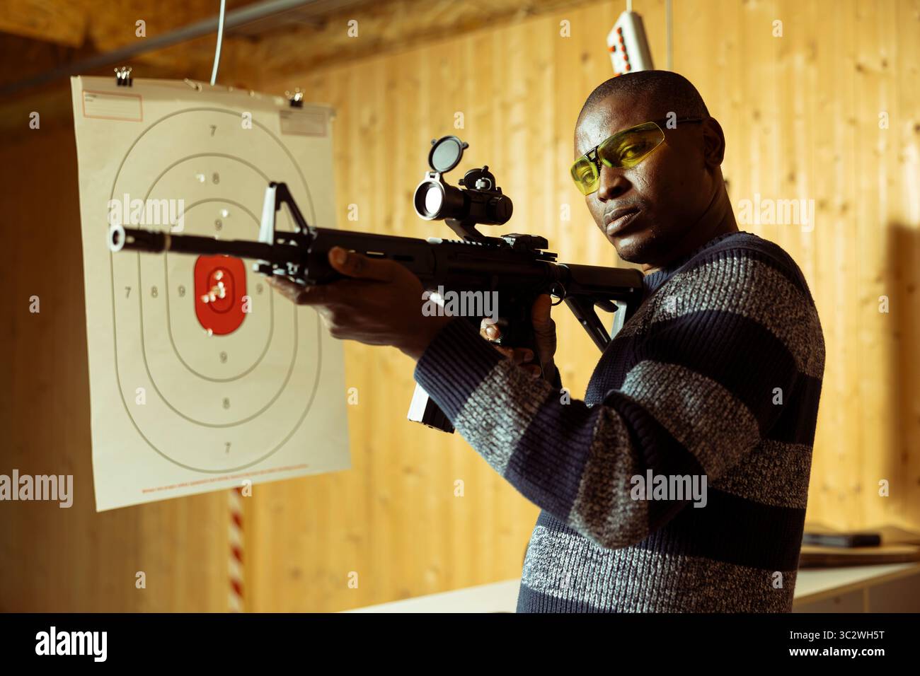 Portrait of man holding rifle enjoying fun indoor shooting experience ...