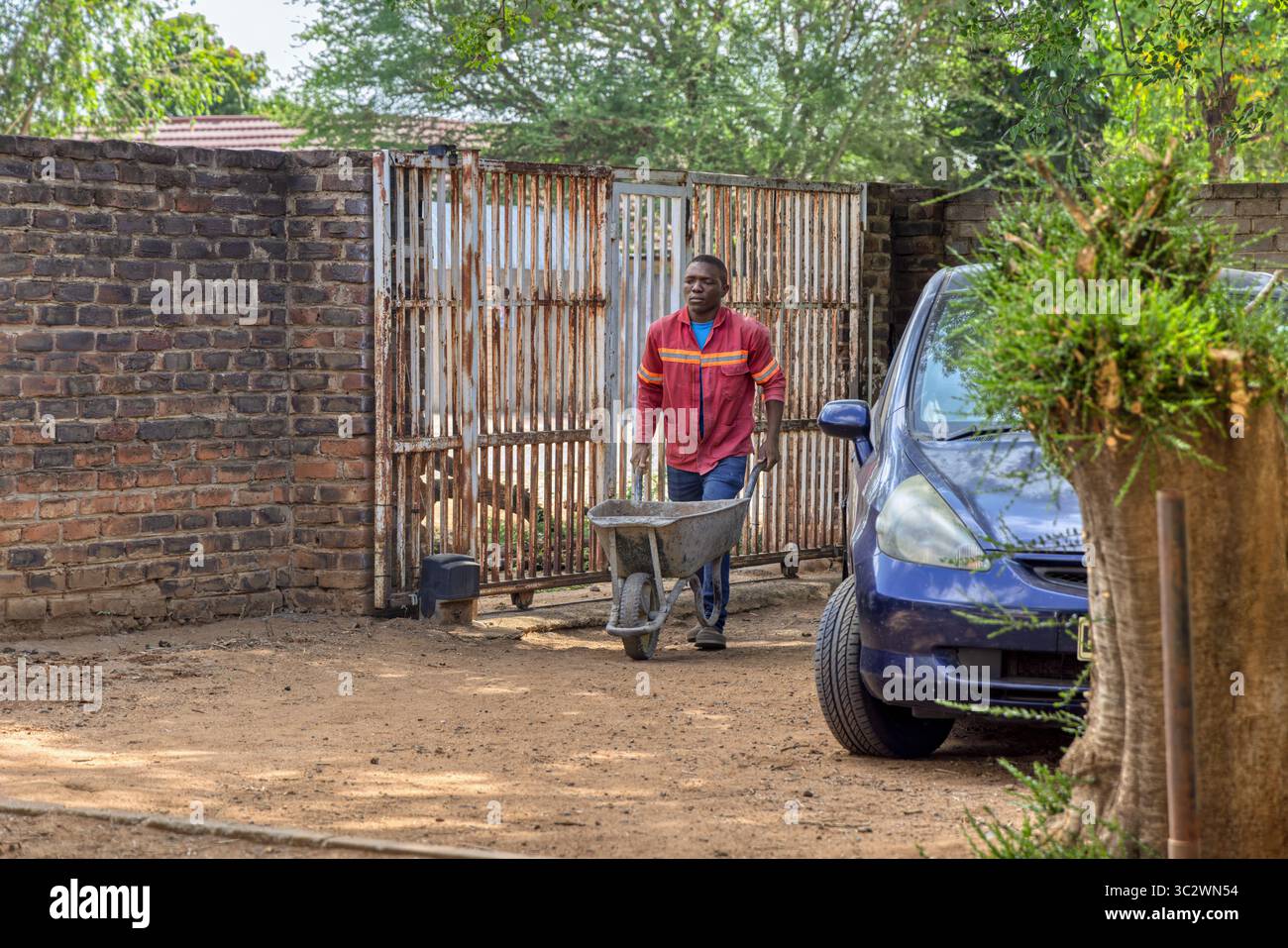 african man in workwear carry a wheelbarrow in the yard Stock Photo - Alamy