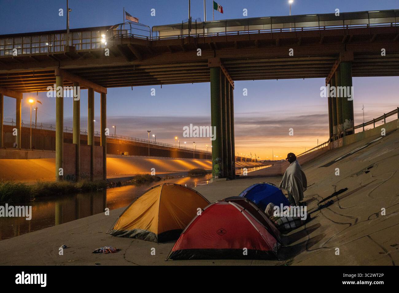 Tents under bridges in a canal near Ciudad Juarez, with national flags ...