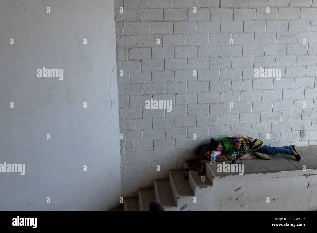 A migrant sleeps on a stair in Ciudad Juarez, highlighting urban ...