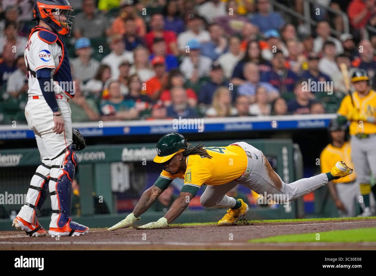 Athletics' Lawrence Butler (4) dives toward home plate to score as ...