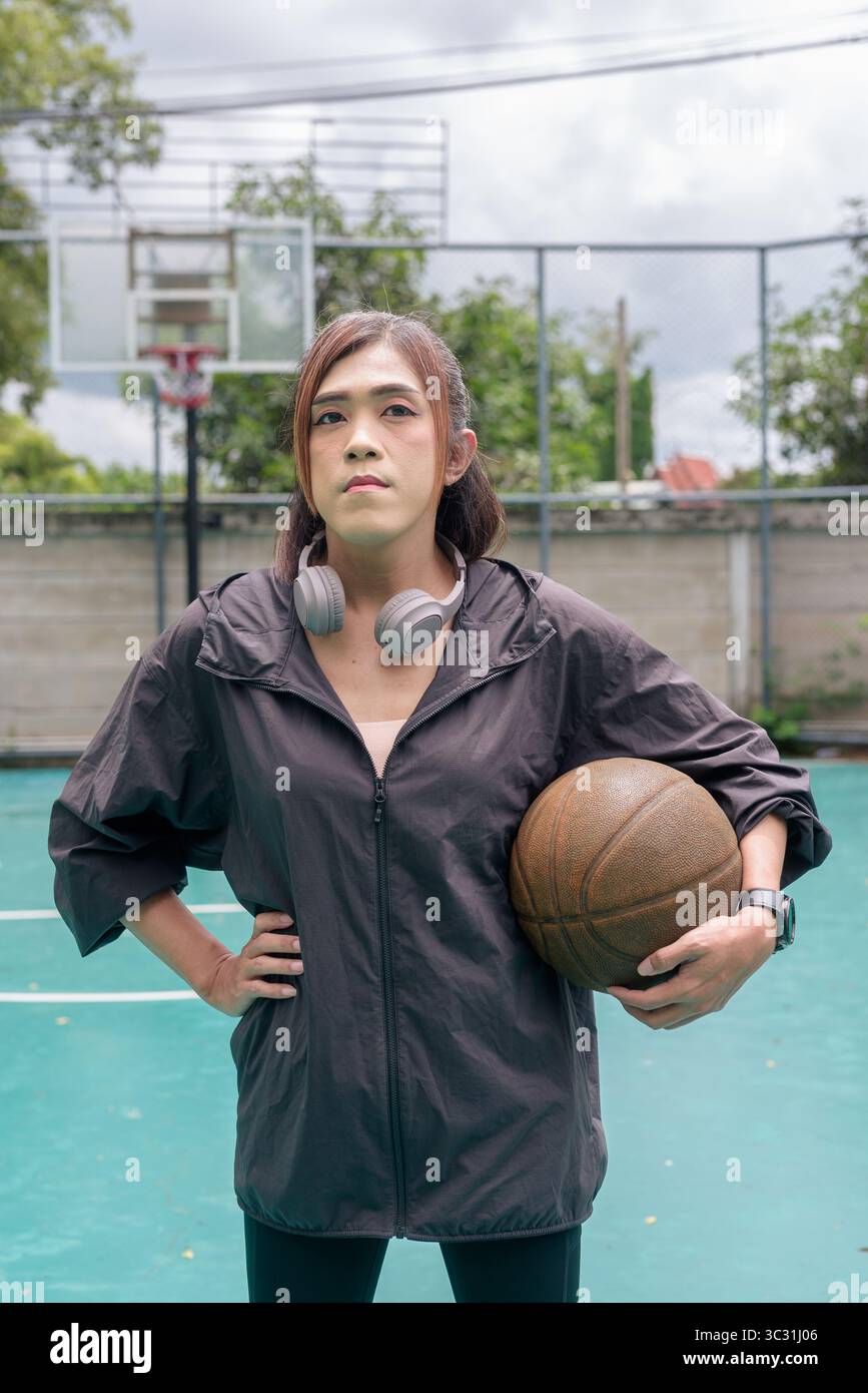 Portrait of a fit transgender woman standing on outdoor basketball ...
