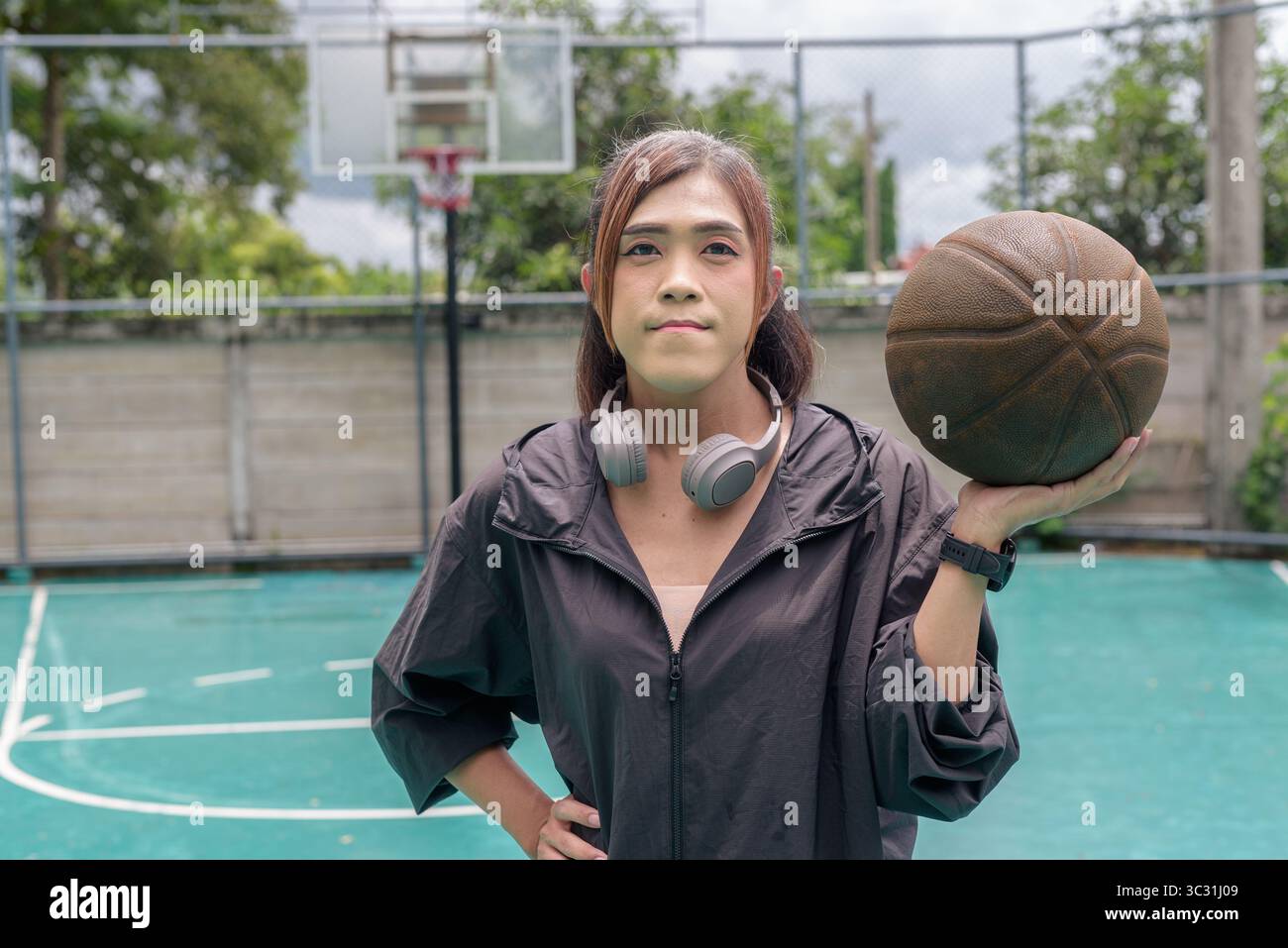 Portrait of a fit transgender woman standing on outdoor basketball ...