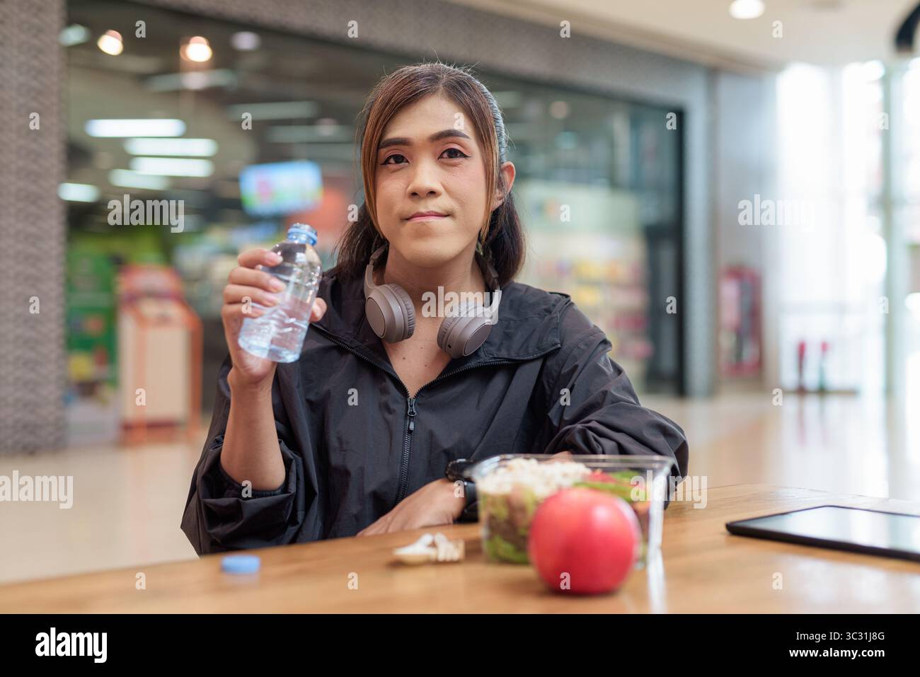 Mature transgender woman eating healthy salad with apple and water in ...