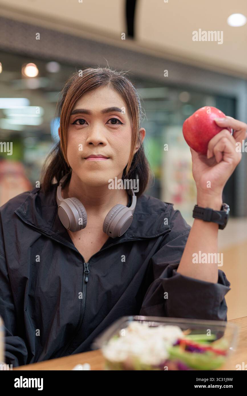 Mature transgender woman eating healthy salad with apple and water in ...