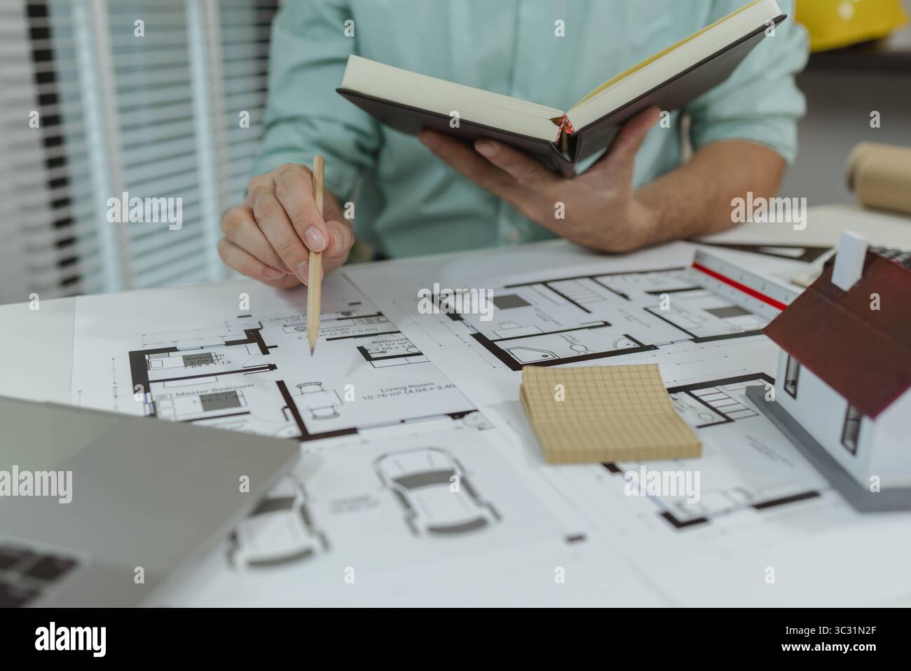 Architect reviewing house floor plan while holding a notebook and ...