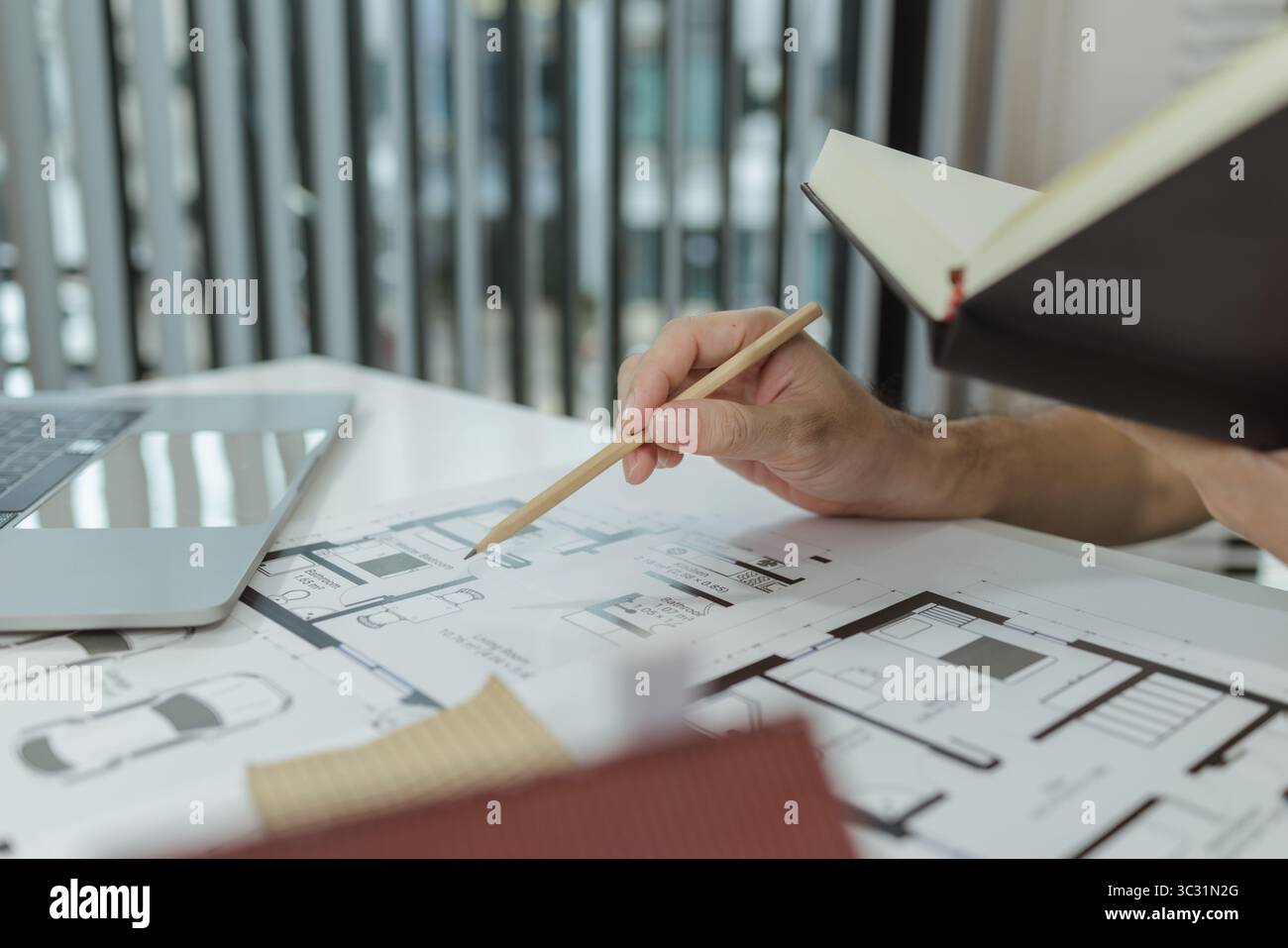 Architect reviewing house floor plan while holding a notebook and ...
