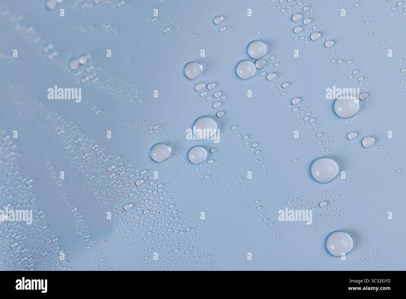 a smooth surface of light blue color covered with water droplets, a ...
