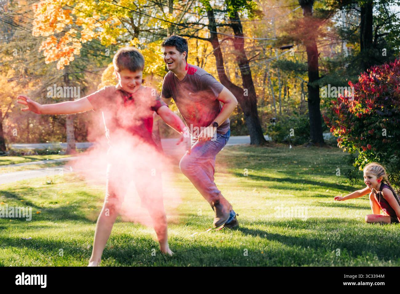 Children playing with colored powder are having fun with their father ...
