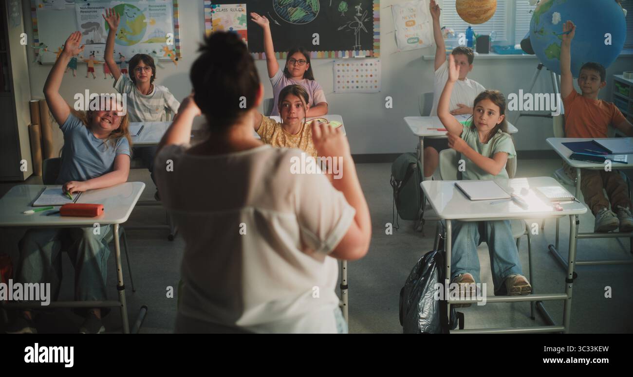 Back View of Female Teacher Conducting Lesson to Elementary School Students, Asking Question ...