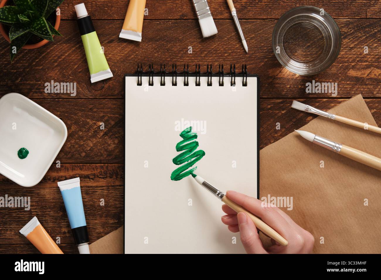 Hand painting a simple green Christmas tree on a sketchbook. Holiday ...