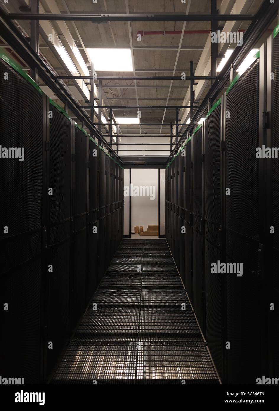 Dark server room corridor featuring metal grid floor and server ...