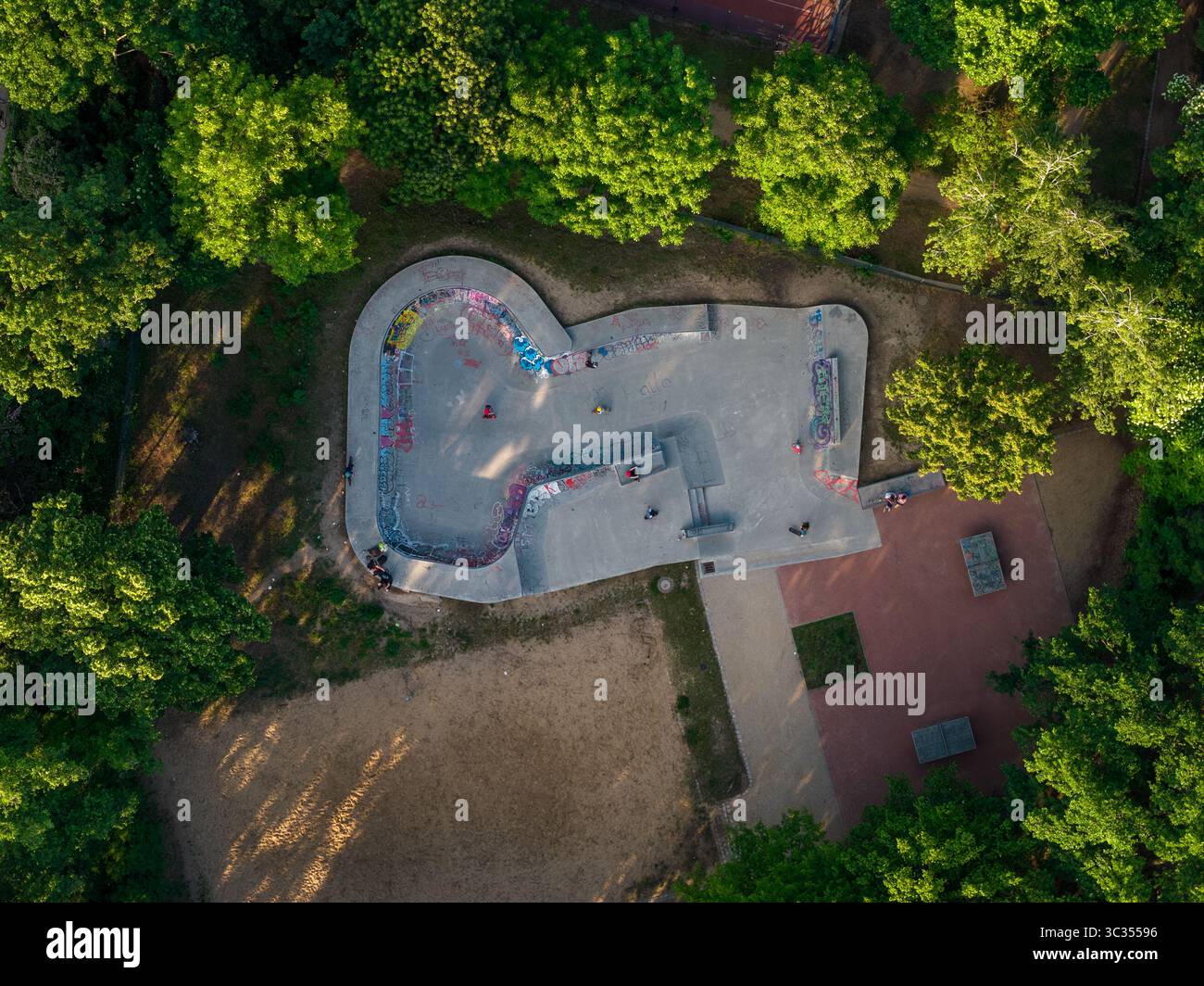 Aerial view of a skatepark surrounded by lush greenery, a concrete ...