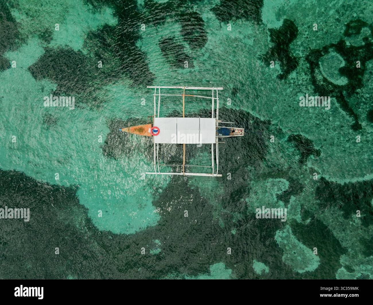 Aerial view of a solitary boat floats over the vibrant turquoise waters ...