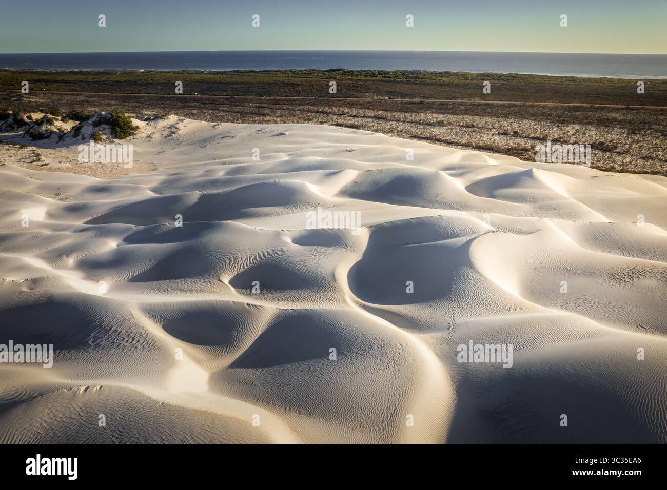 Aerial view of undulating sand dunes contrasting with the distant ocean ...