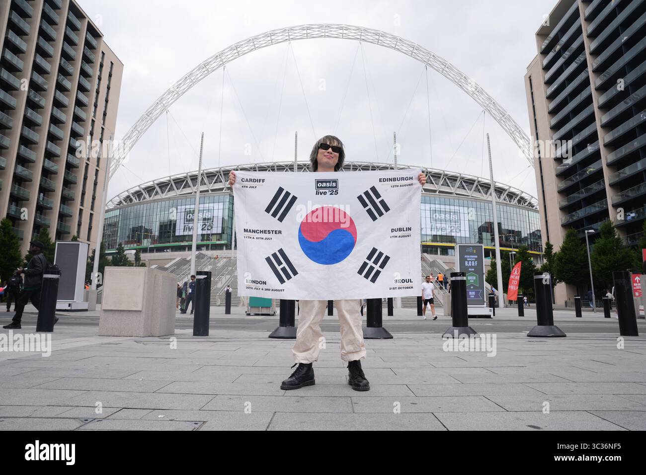 Oasis fans hold a Union Jack themed flag outside the stadium, ahead of ...