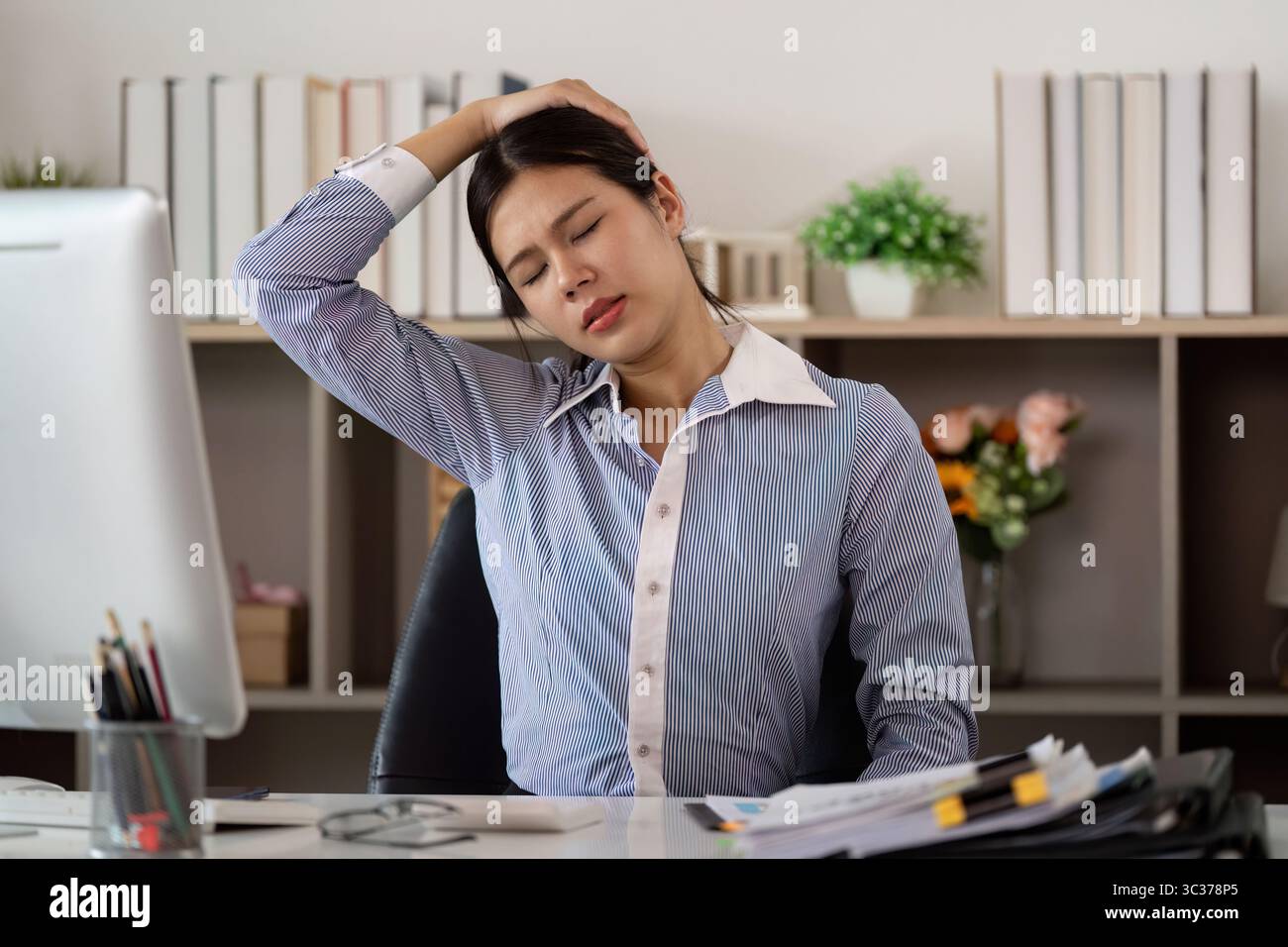 Office Syndrome: Woman stretching neck to relieve tension at her desk ...