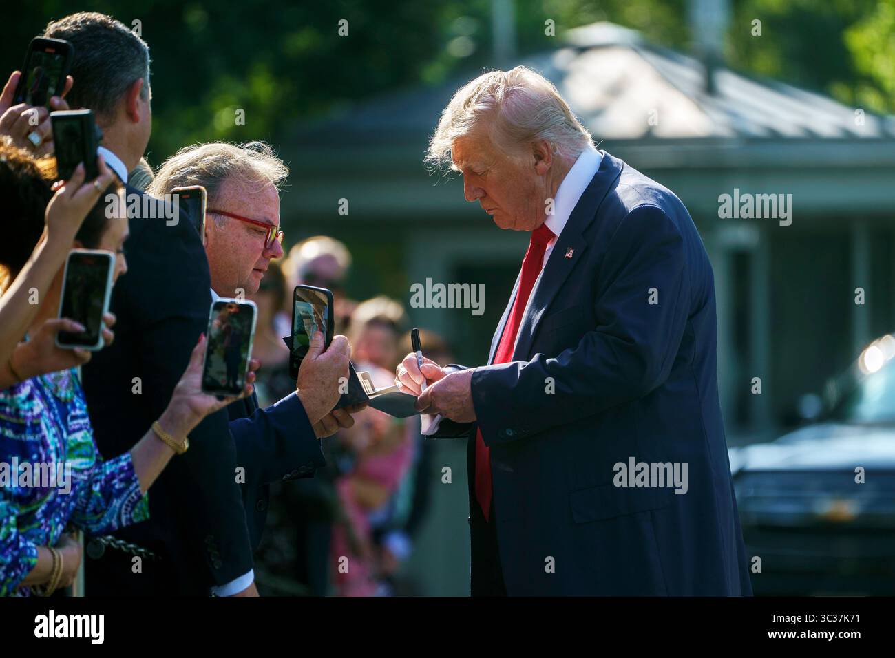 US President Donald Trump signs an autograph for a guest as he leaves ...