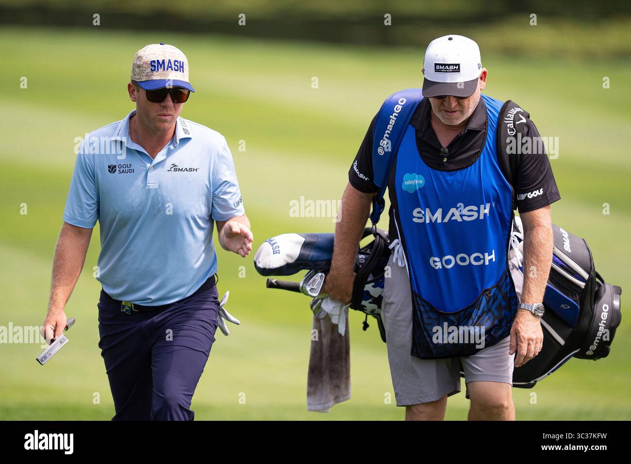 Talor Gooch, of Smash GC, and his caddie, Malcolm Baker, walk on the first hole during the first ...