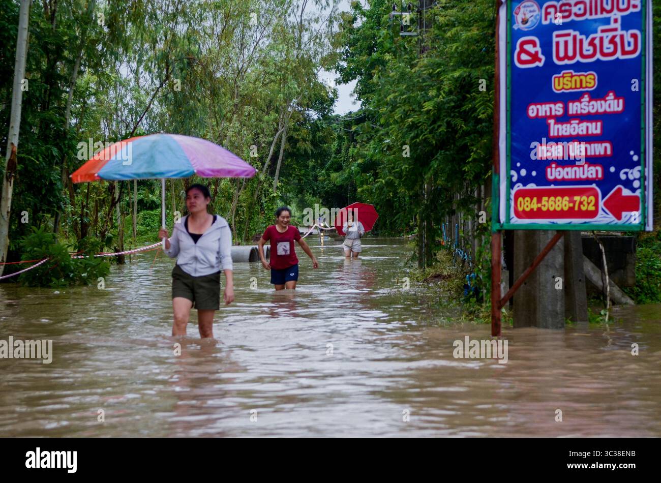 Women are walking out from a flooded neighborhood onto a main road in ...