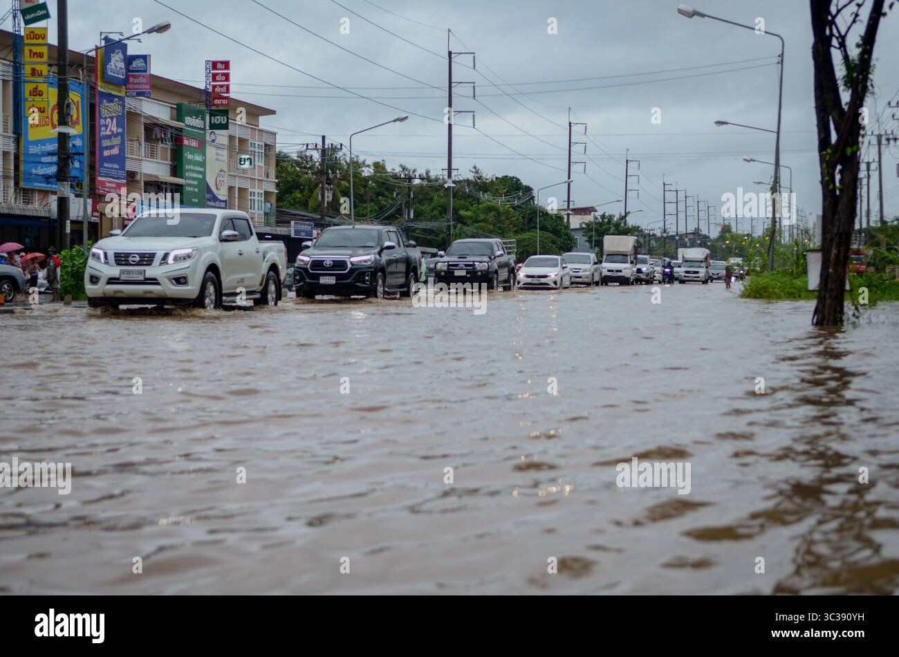 Vehicles move slowly as floodwaters submerge one side of a main road in ...