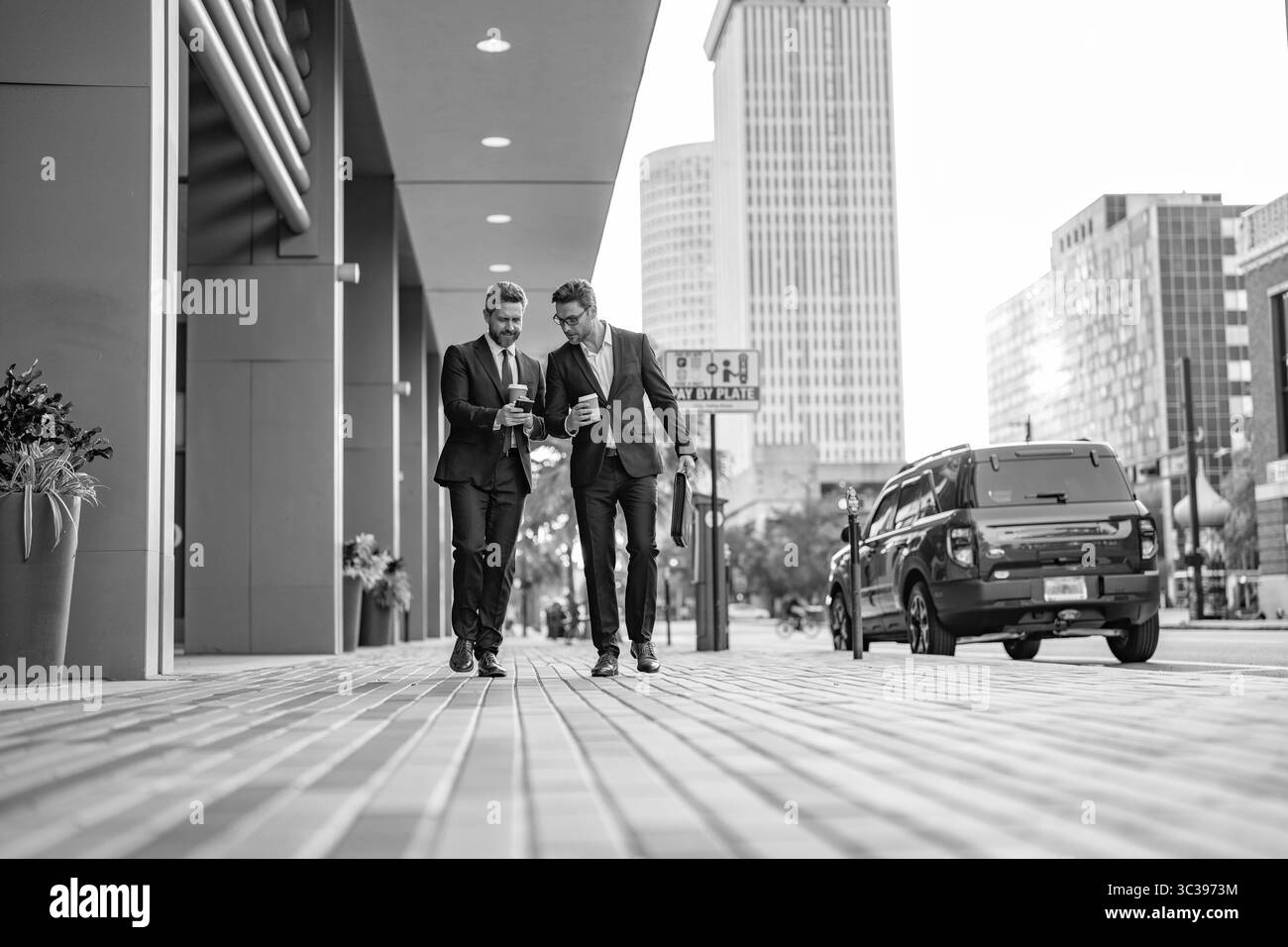 Two businessmen walking and talking in the city. Business men talking. Walking and talking two ...