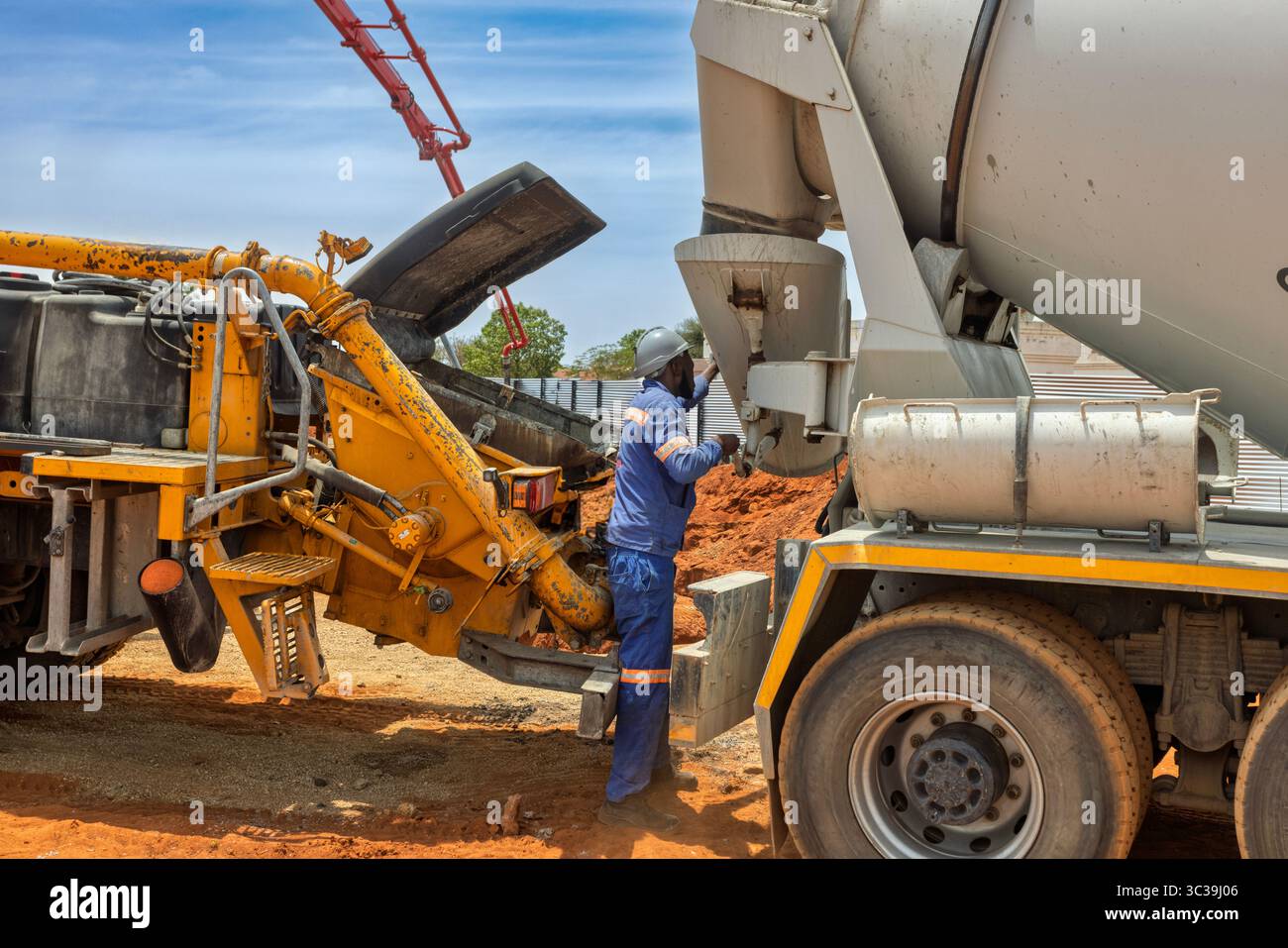 a cement mixer truck link to a concrete pump crane, An African American construction worker ...