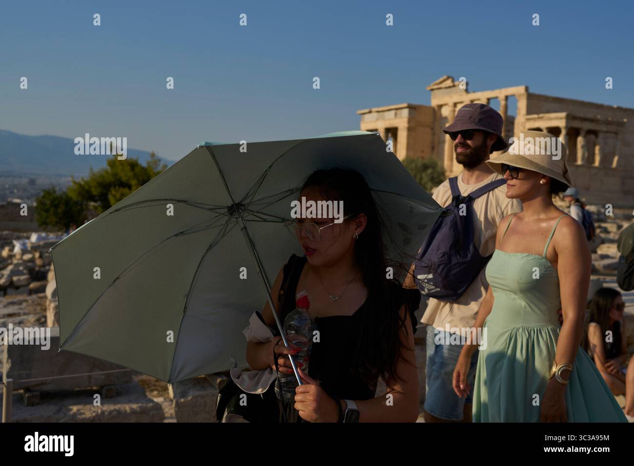 A tourist holds an umbrella to shield herself from the sun as she walks ...