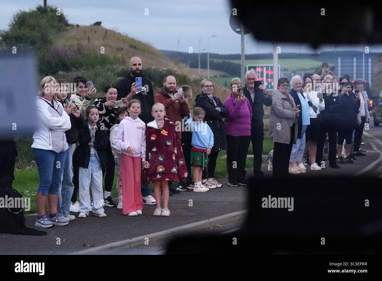 Onlookers take pictures as the convoy with President Donald Trump ...