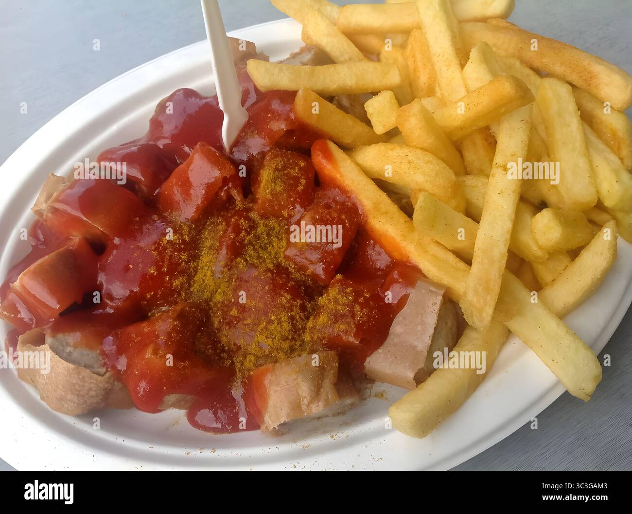 Traditional German currywurst with fries, served with wooden fork on ...