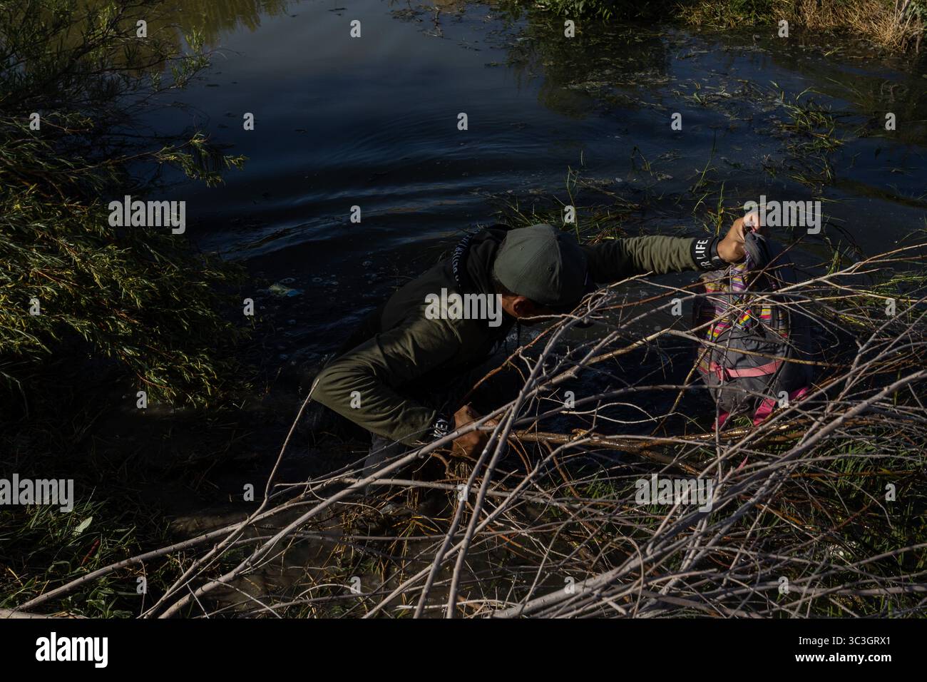 Man and child navigate treacherous river debris while crossing Ciudad ...