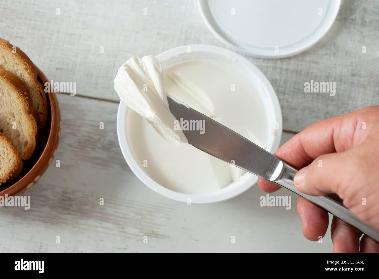 A top down view of a hand using a butter knife to spread dairy-free ...