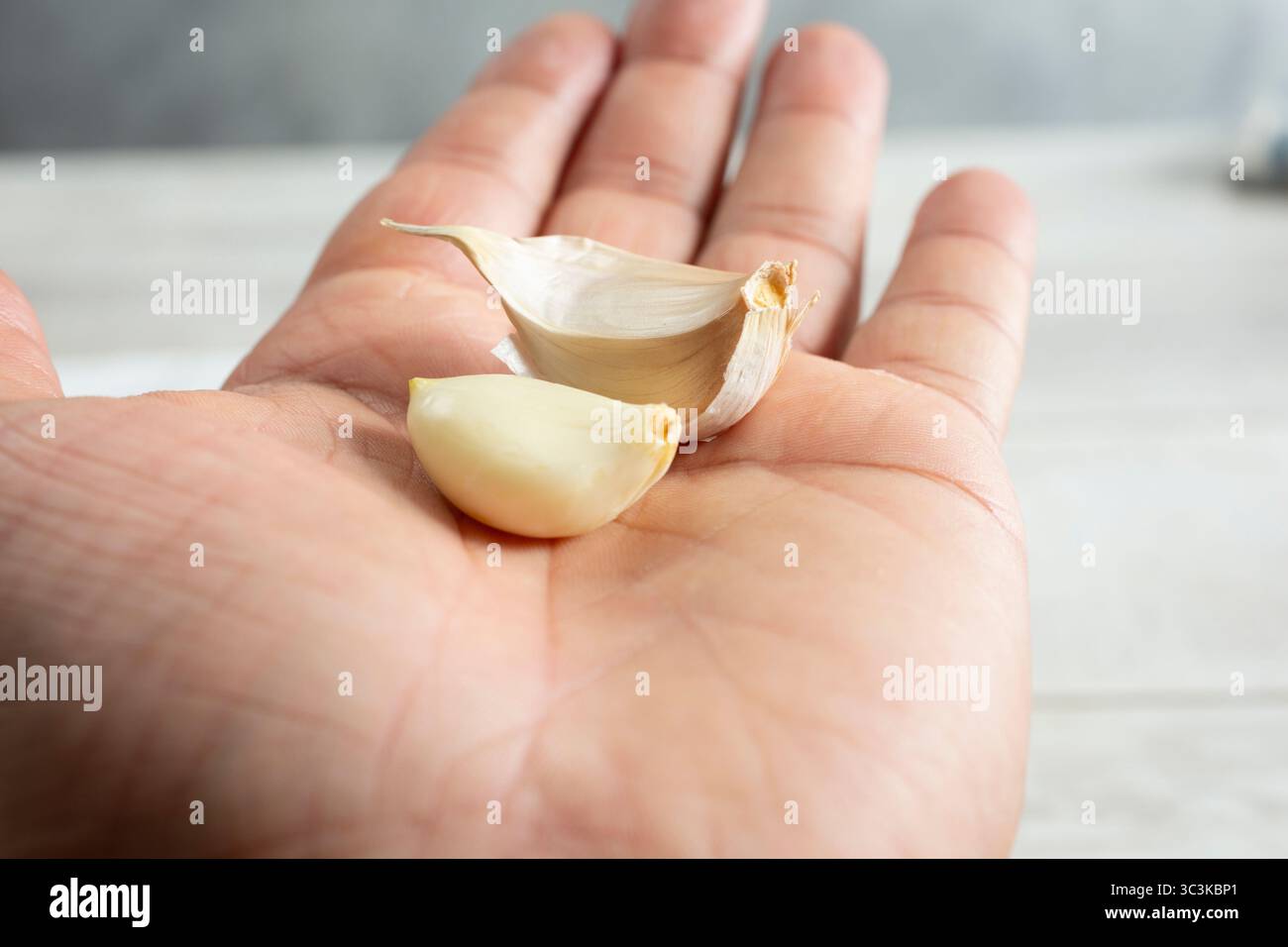 A view of a peeled garlic clove and unpeeled garlic clove in the palm ...